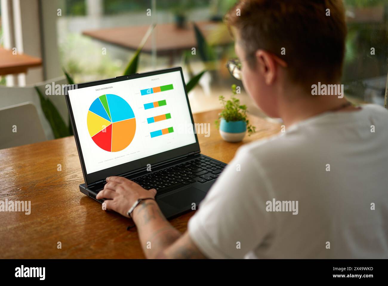 Transgender office worker analyzes data charts on laptop screen in ...