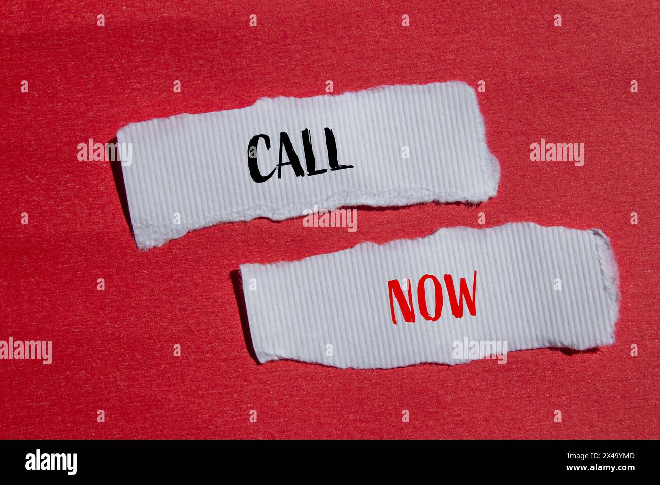 Call now words written on ripped white paper pieces with red background ...