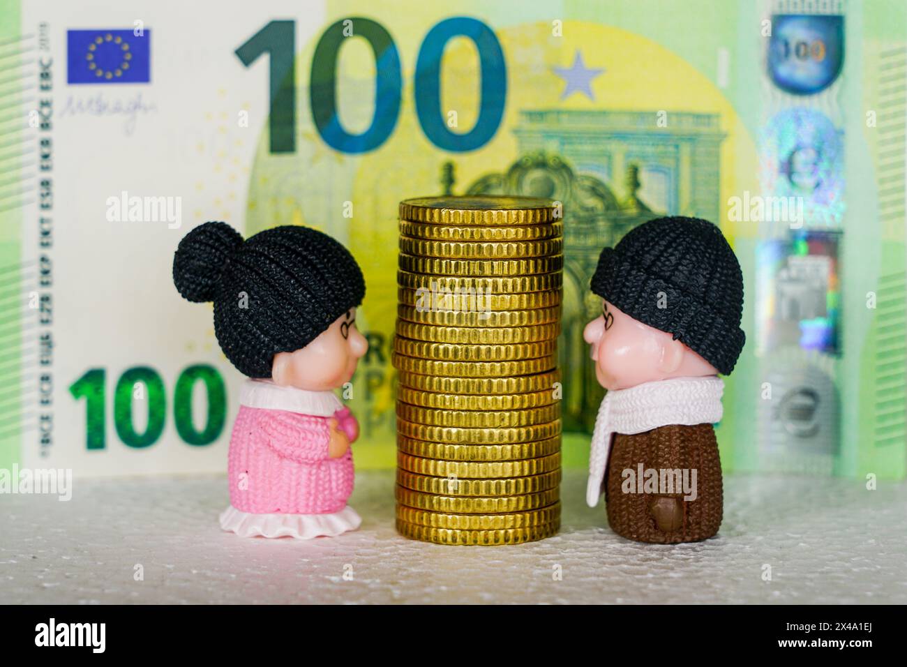 High stack of yellow coins between toy figures of elderly man and woman ...