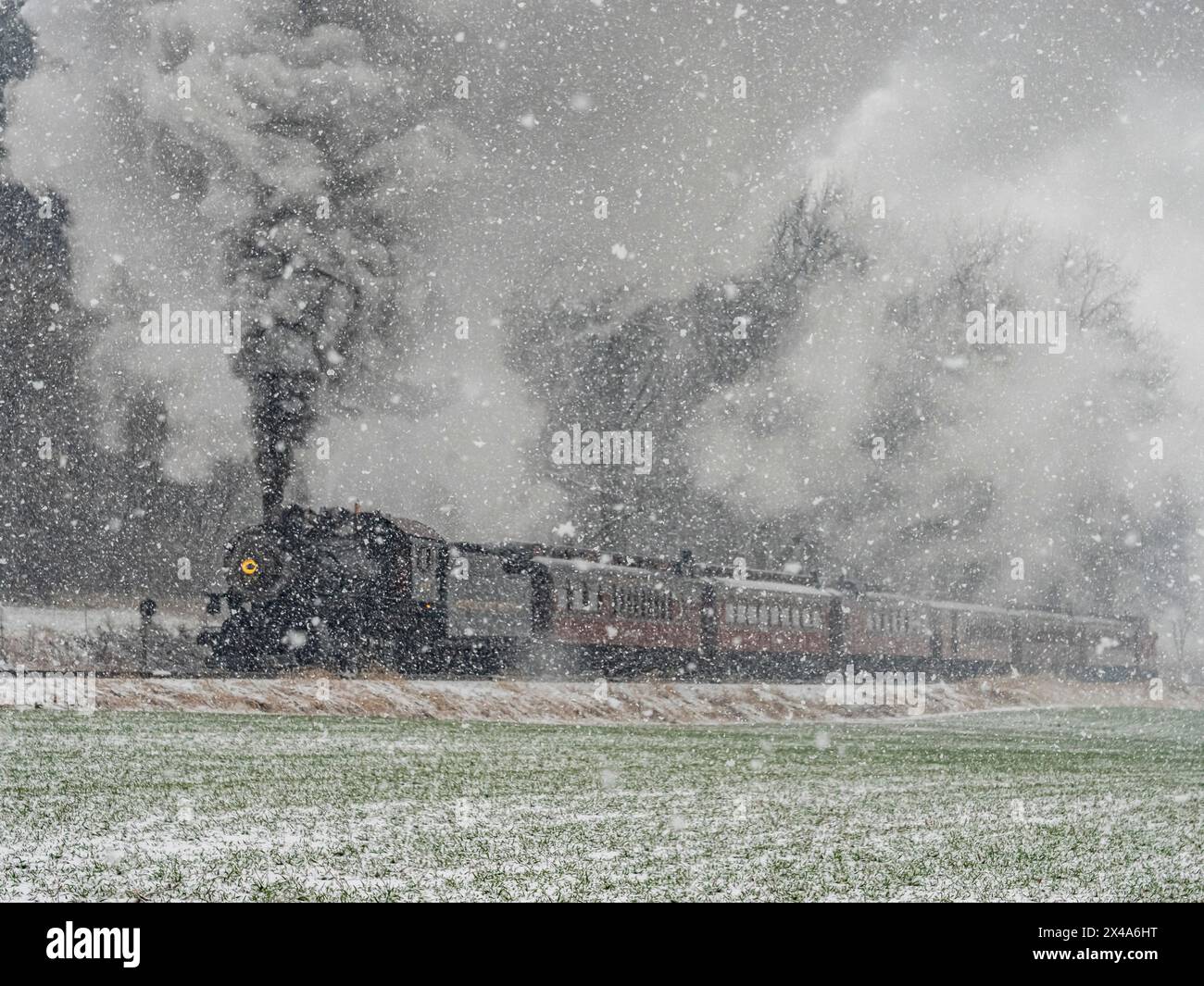 A train is traveling through a snowy field. The steam from the train is ...