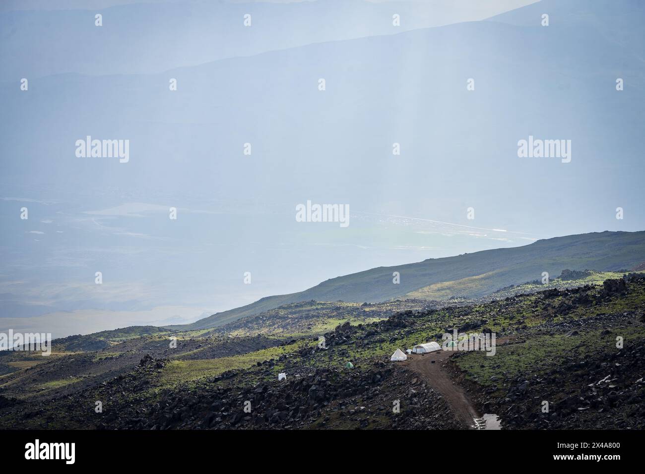 Mountain tent campsite set on the side of the mountain hit by soft noon ...