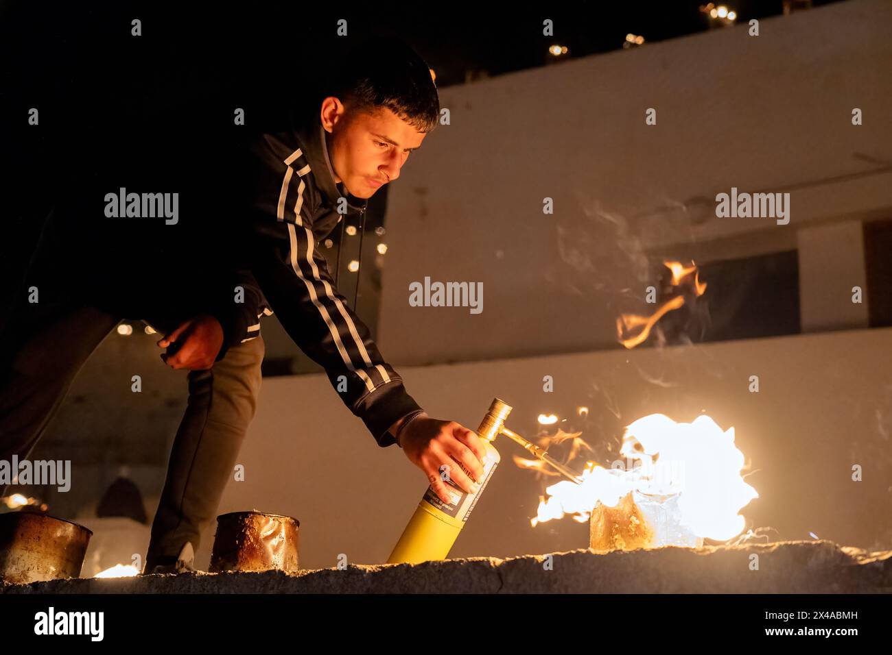 A young white, Caucasian man lights up one of the thousands of lanterns ...