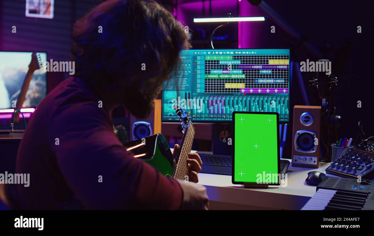 Sound engineer practices playing acoustic guitar using learning app ...