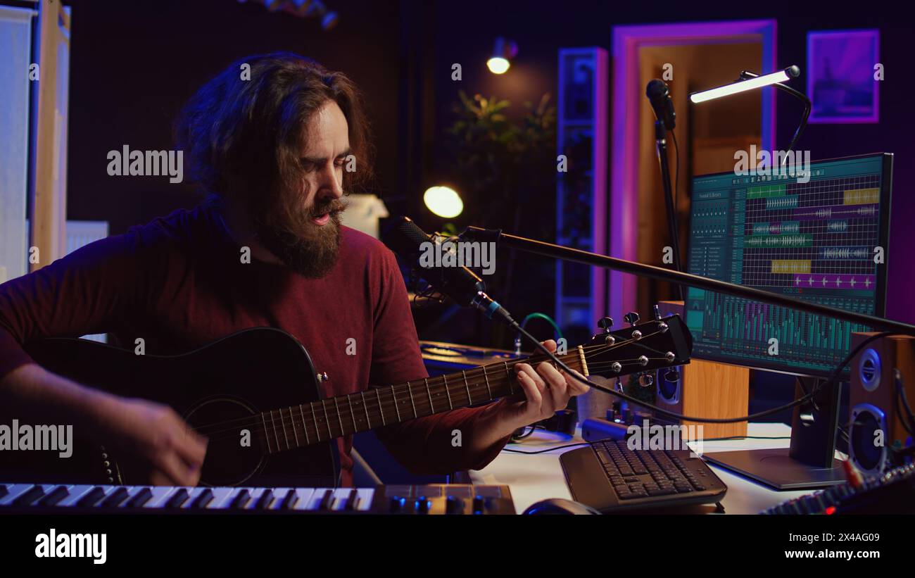 Creative songwriter singing a song on microphone and playing his guitar ...