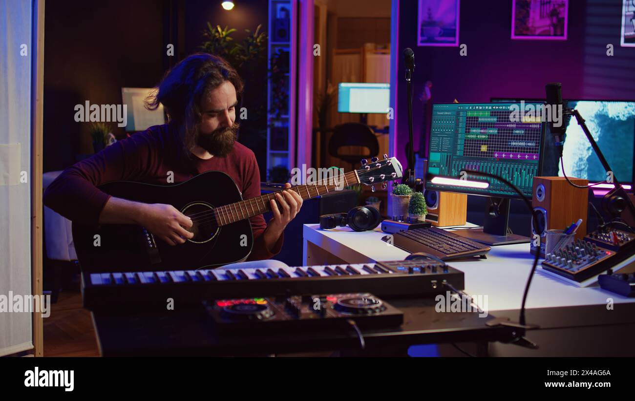 Music producer tuning his acoustic guitar before playing instrument ...