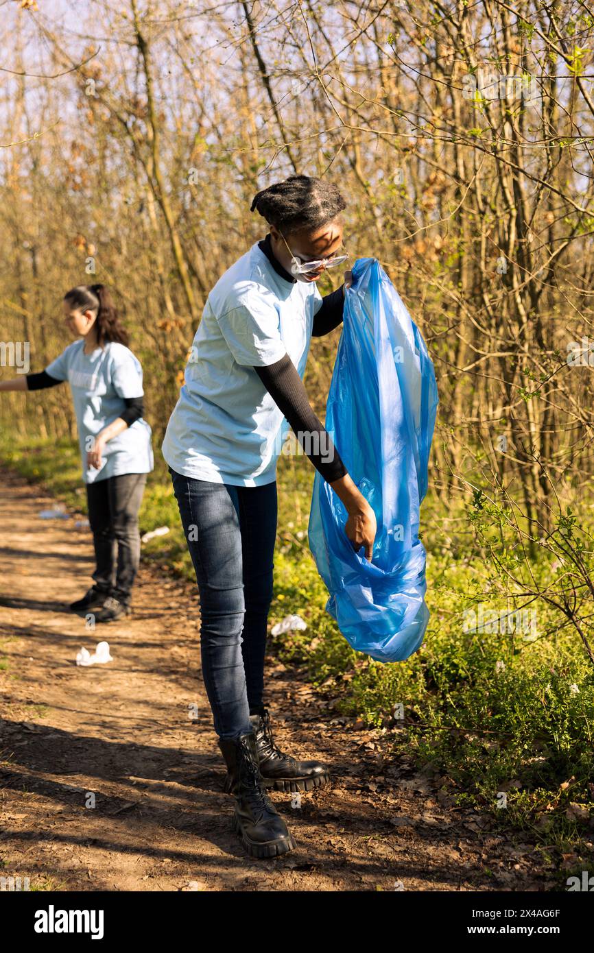 Woman volunteer grabbing junk and plastic waste with a claw tool ...