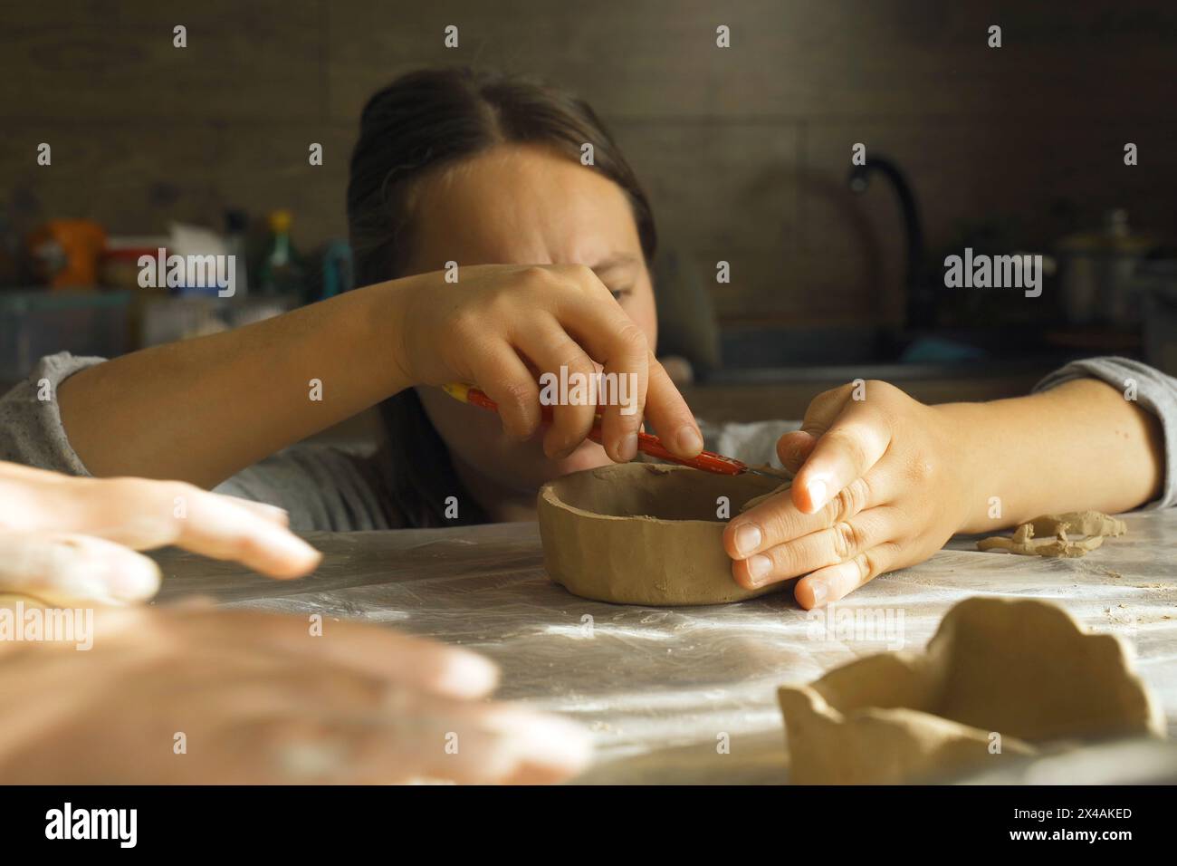 The woman shapes the product and cuts off excess clay from the walls of ...