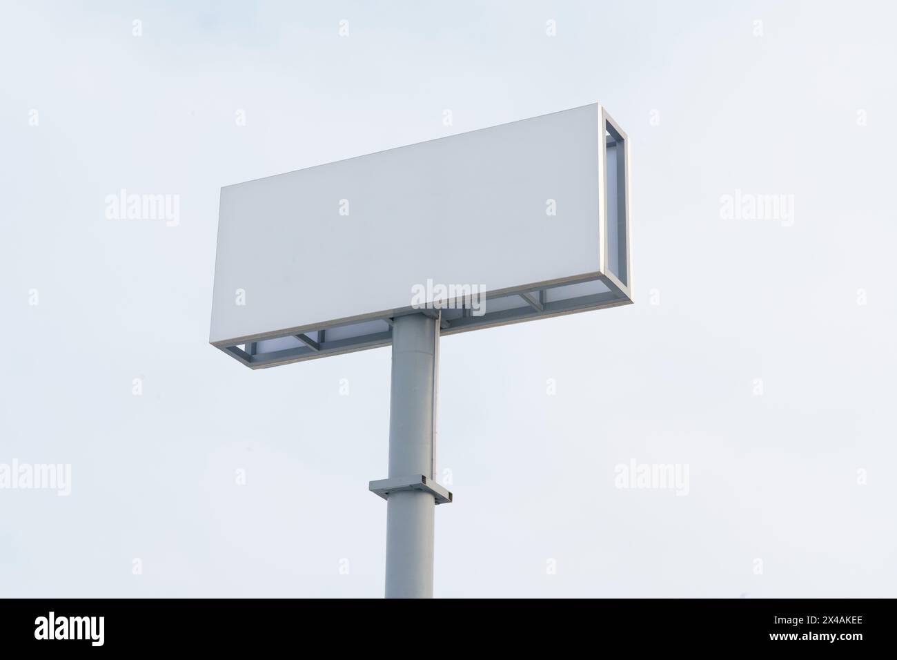 A large white sign stands on top of a metal pole against a white ...
