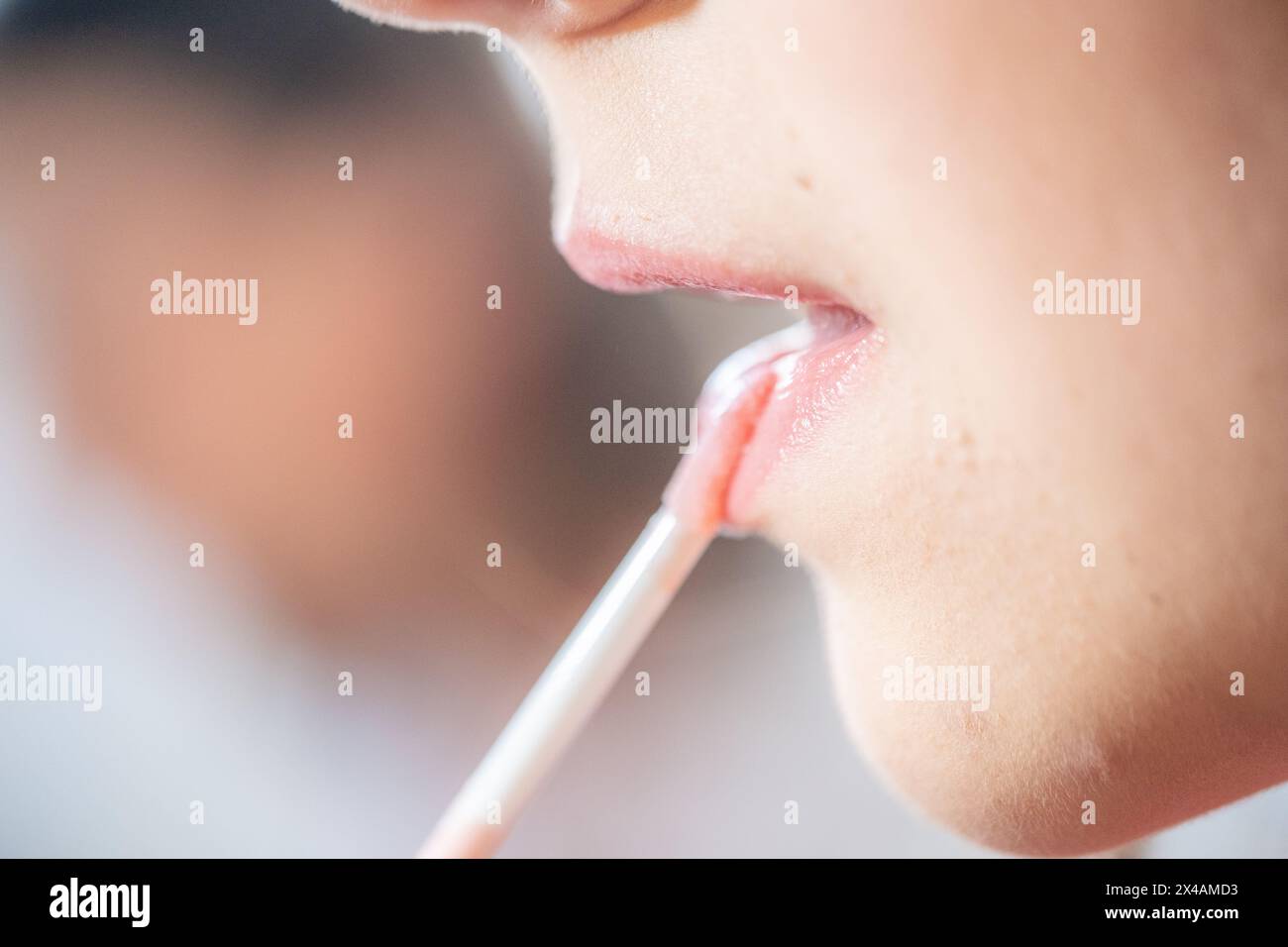 Detail of a young teenager in profile painting her lips with a small ...