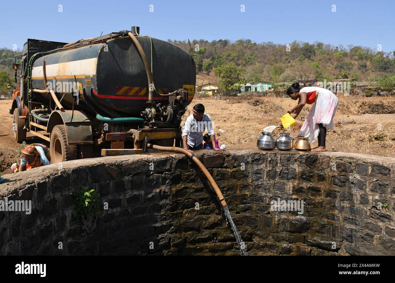 A man empties water from a tanker truck into the well near Vihigaon ...