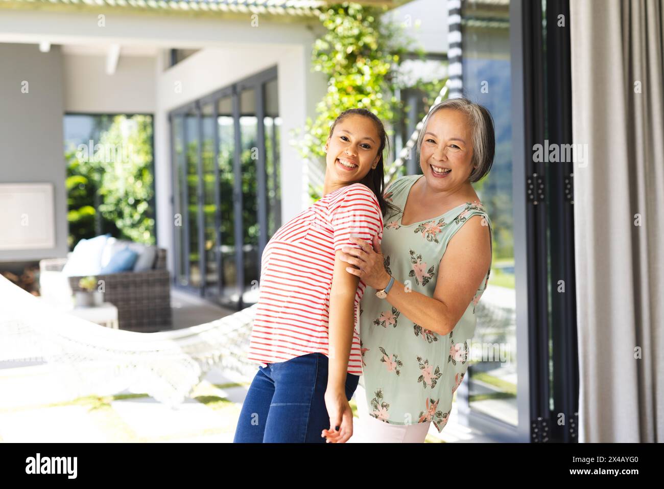 Asian grandmother and biracial teenage granddaughter smiling together ...