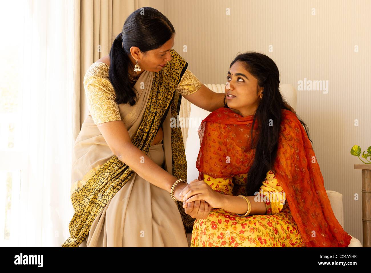 Indian mother in sari comforting teenage daughter, both in traditional ...
