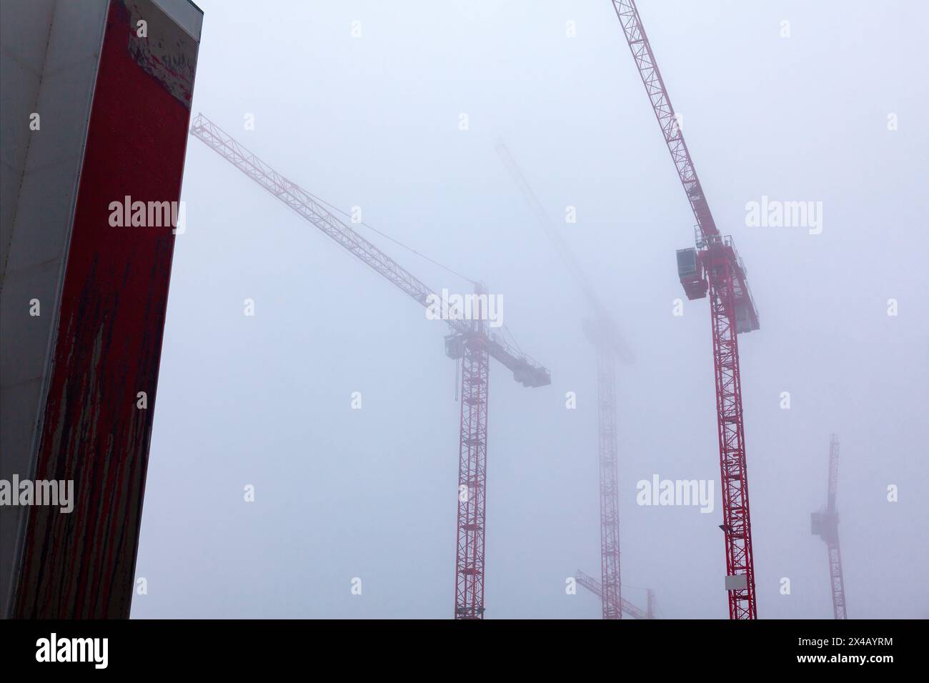 Construction cranes and buildings in the fog. Tower cranes in a foggy ...