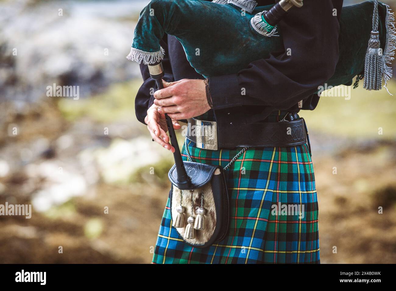 A man wearing a kilt and holding a pipe. The man is dressed in ...