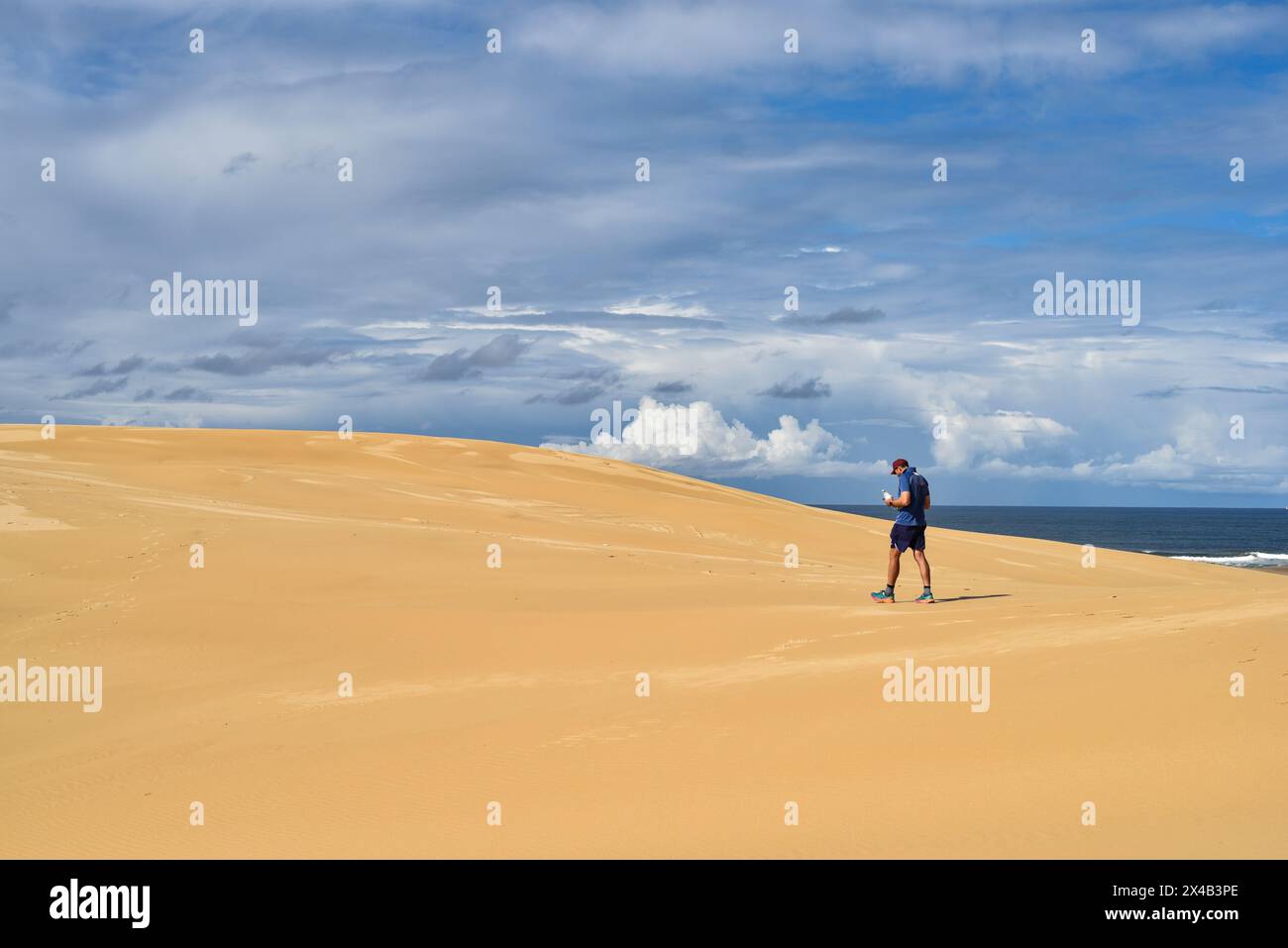 man walking through vast sand dunes Stock Photo - Alamy