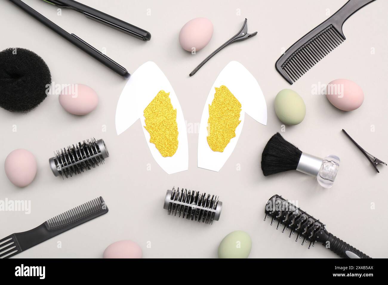 Paper bunny ears with Easter eggs and hairdressing accessories on white ...