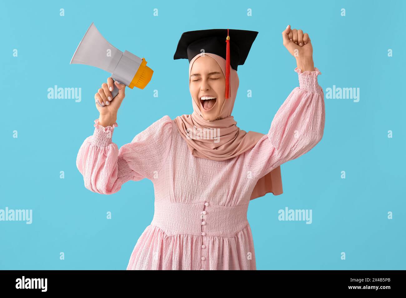 Female Muslim graduate with megaphone on blue background Stock Photo ...