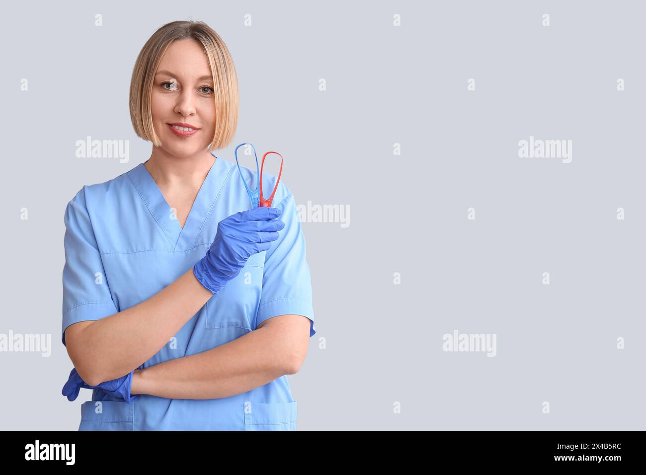 Female dentist with tongue scrapers on grey background Stock Photo - Alamy