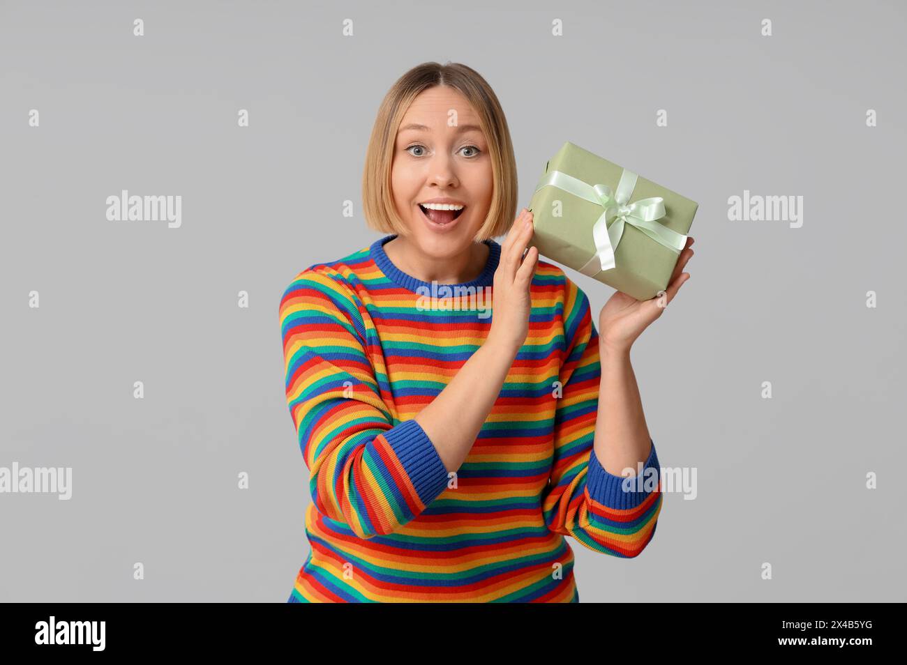 Surprised adult woman with gift box on white background Stock Photo - Alamy