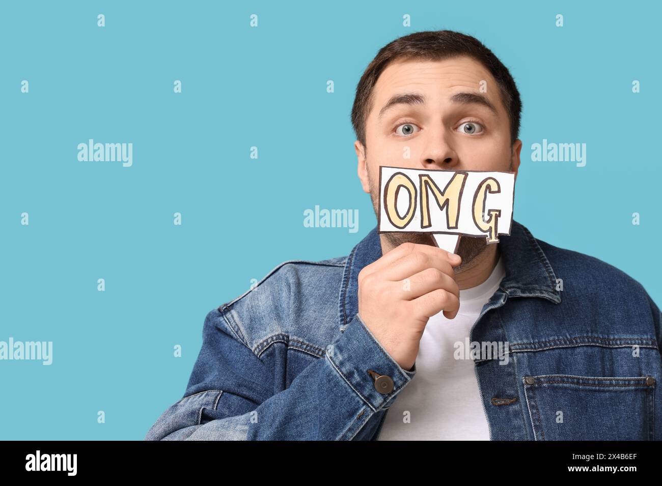 Shocked young man holding text OMG on blue background Stock Photo - Alamy