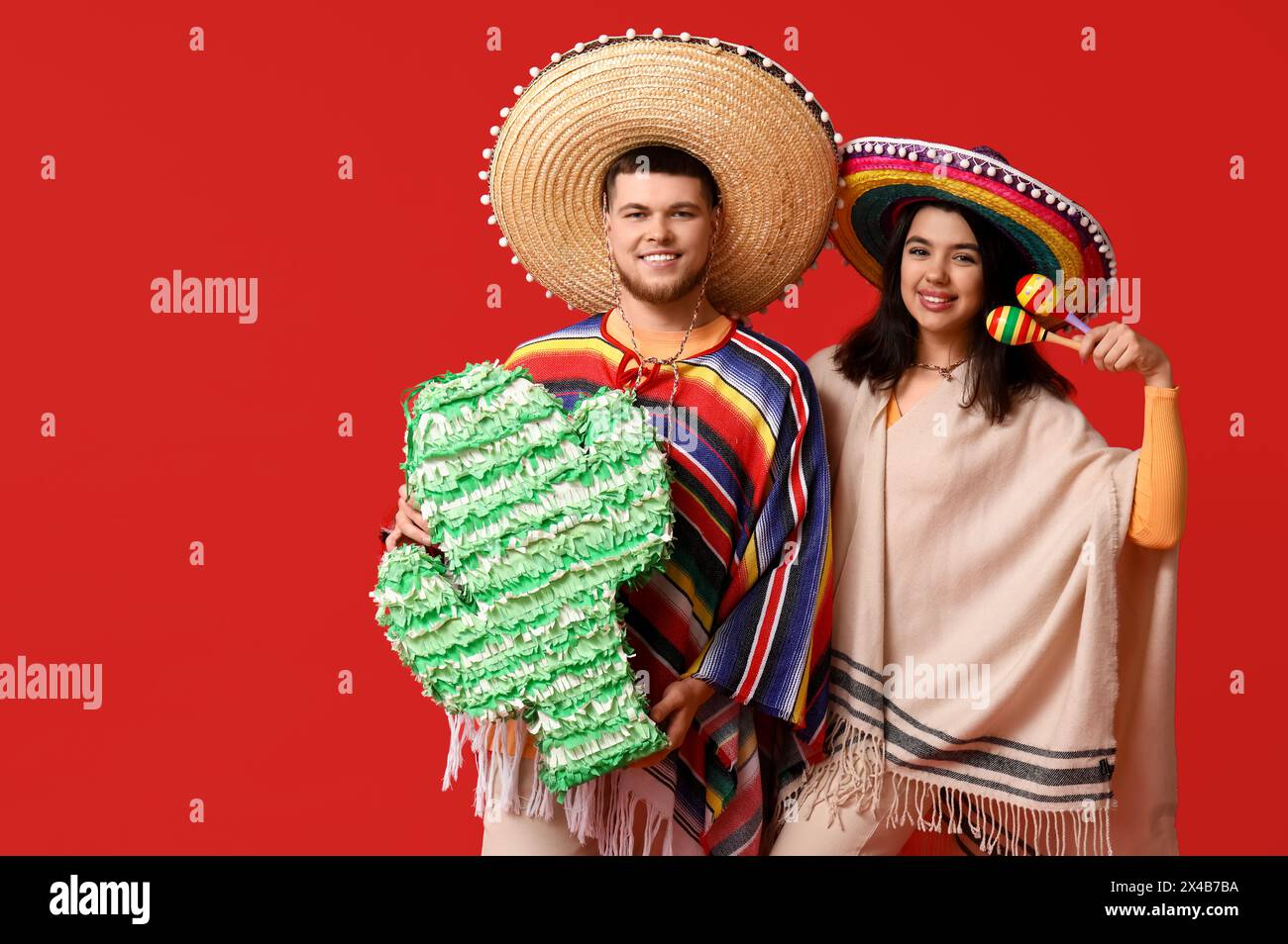 Beautiful young happy couple in sombrero hats with maracas and pinata ...