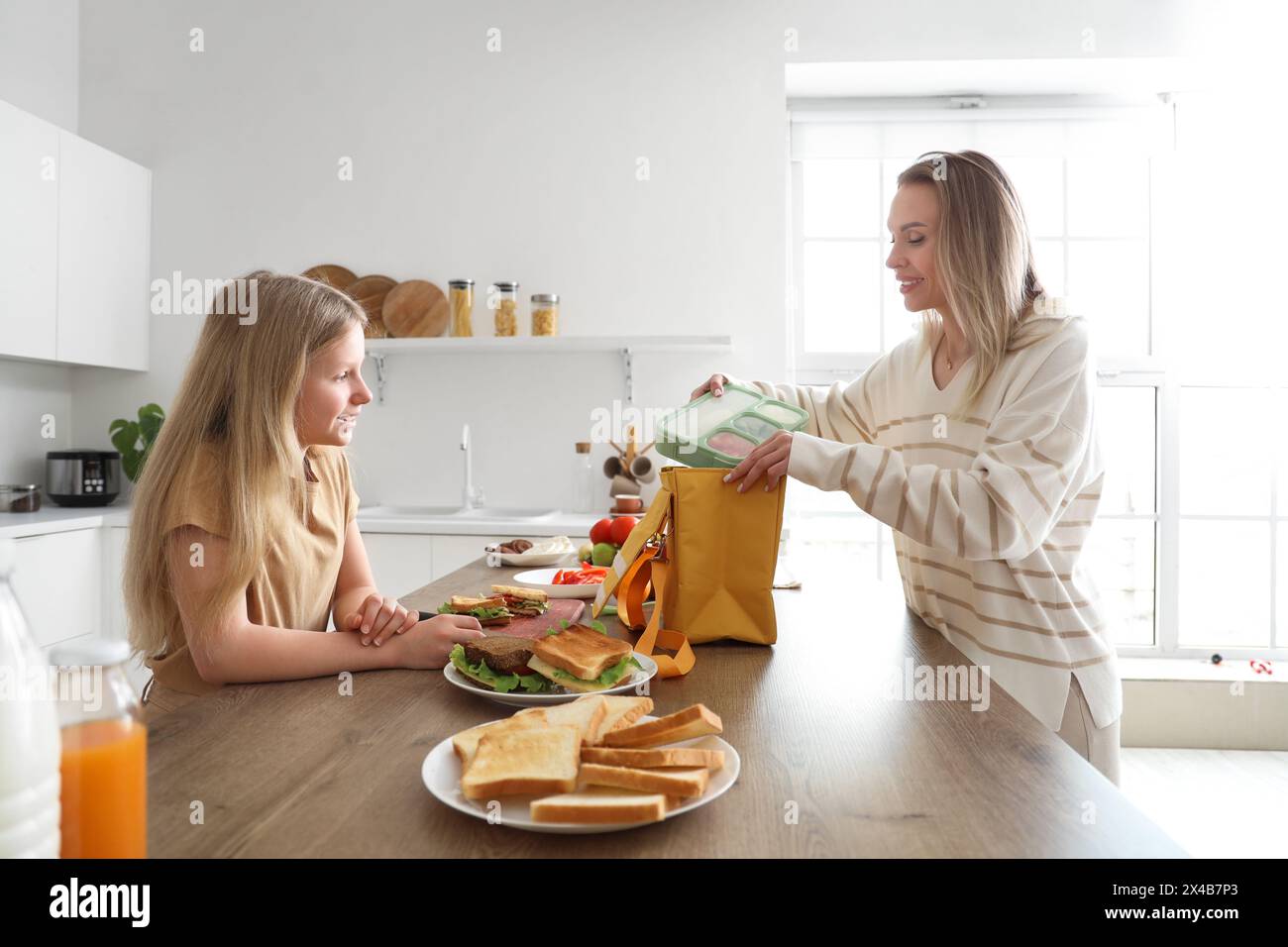 Happy mother with her daughter packing school lunch in kitchen Stock ...