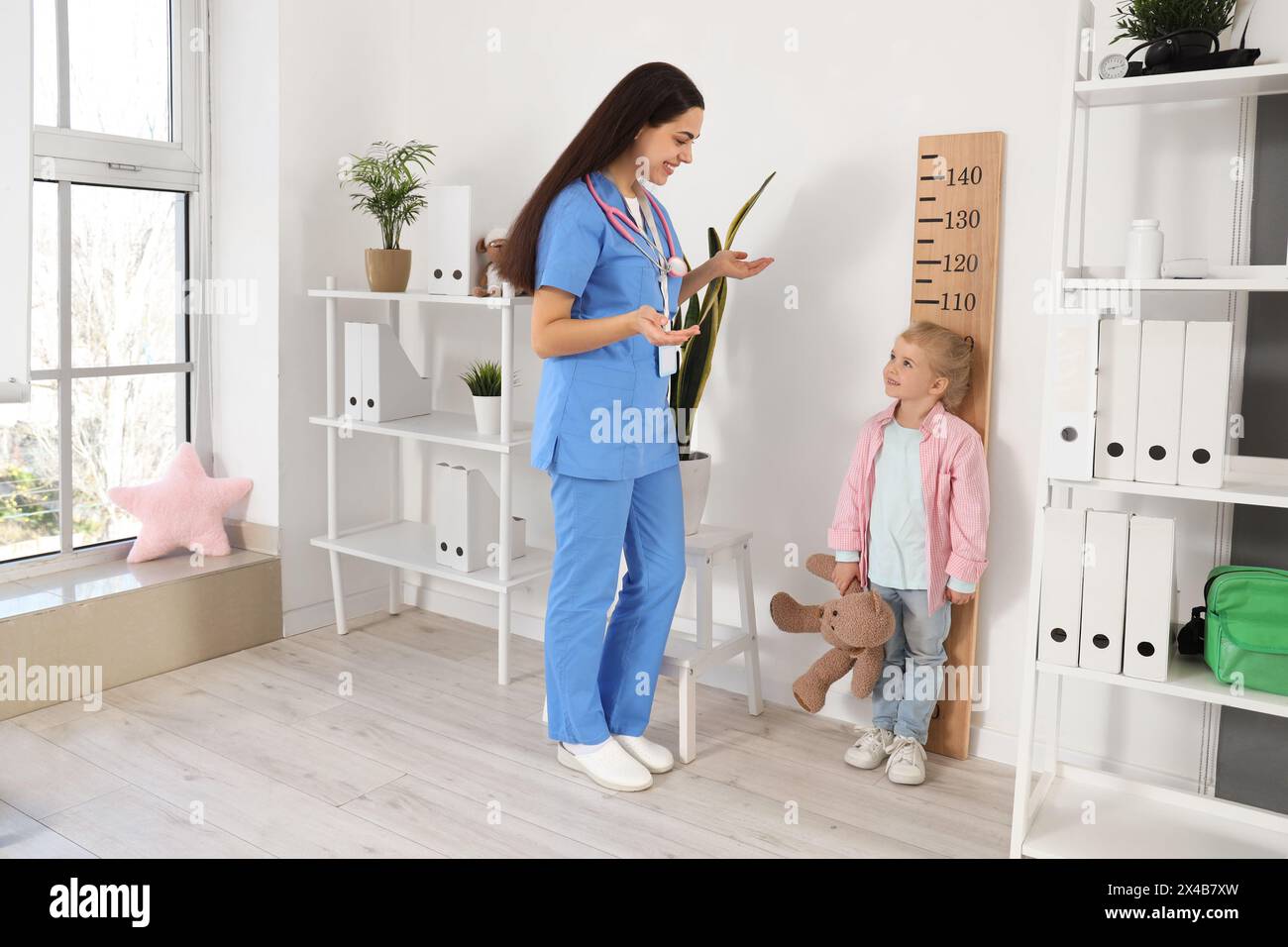 Female pediatrician measuring height of little girl in clinic Stock ...