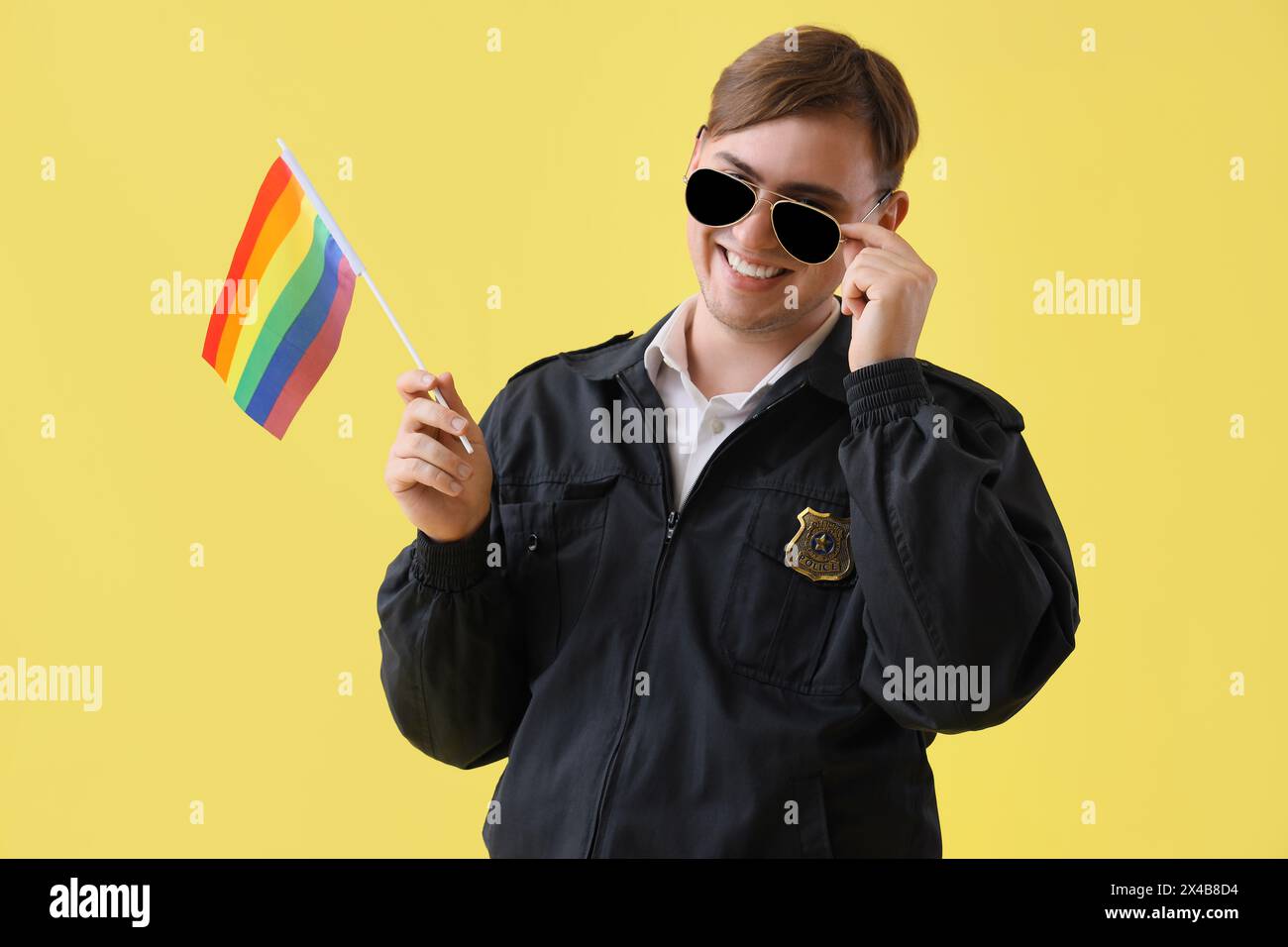 Male police officer with LGBT flag on yellow background Stock Photo - Alamy