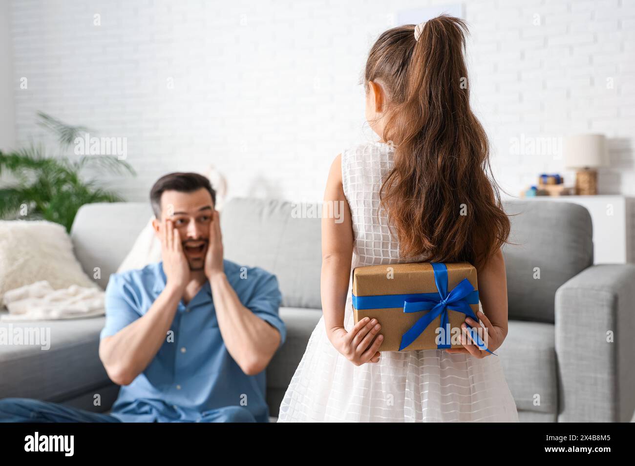 Little daughter making her father surprise in living room. Father's Day ...