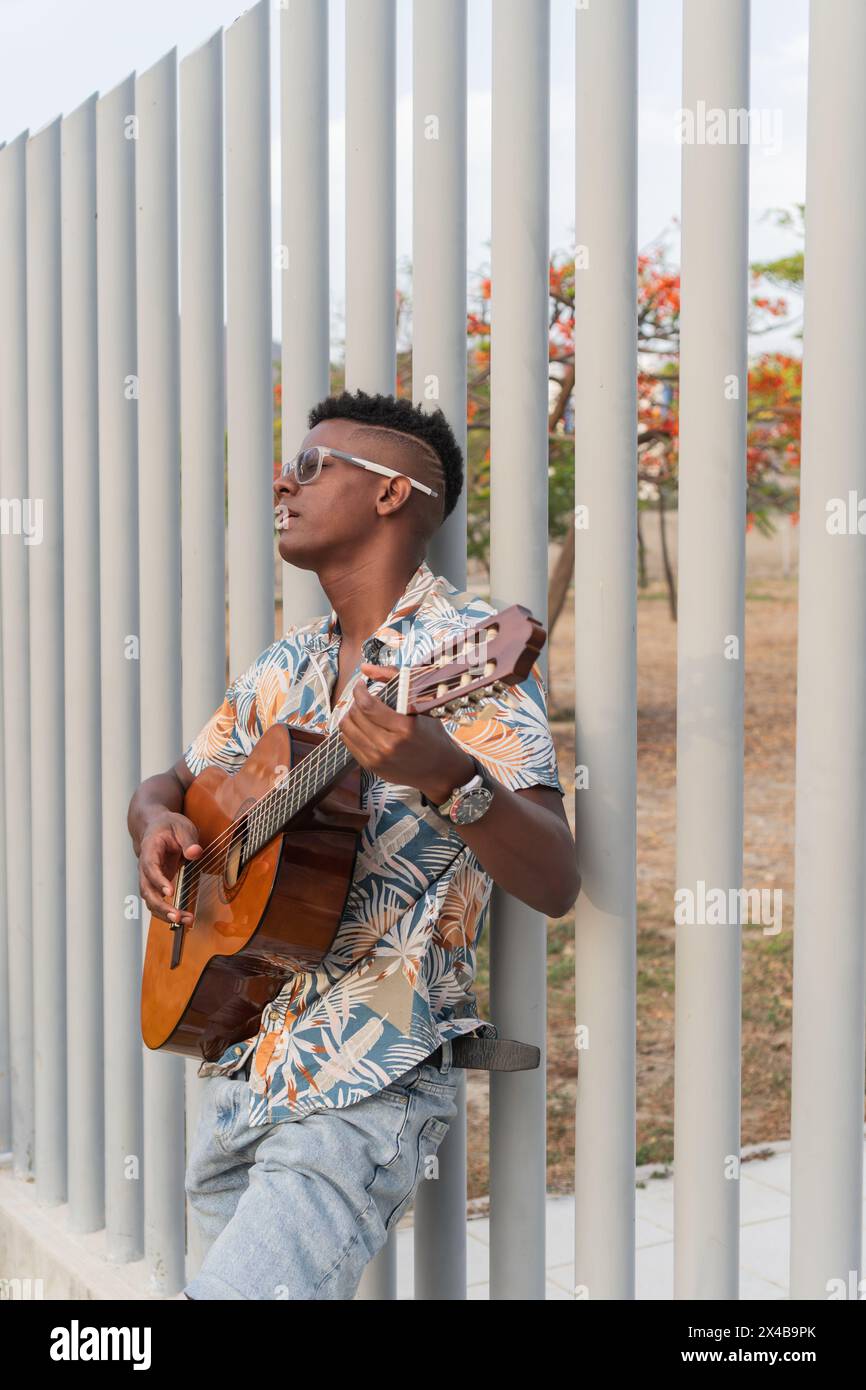 A contemplative young man plays his guitar amidst an urban backdrop ...