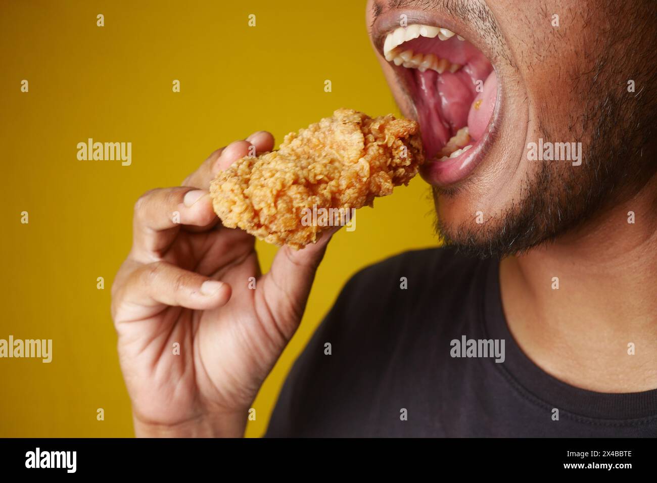 Man enjoying fried chicken, mouth open, savoring every bite with a big ...