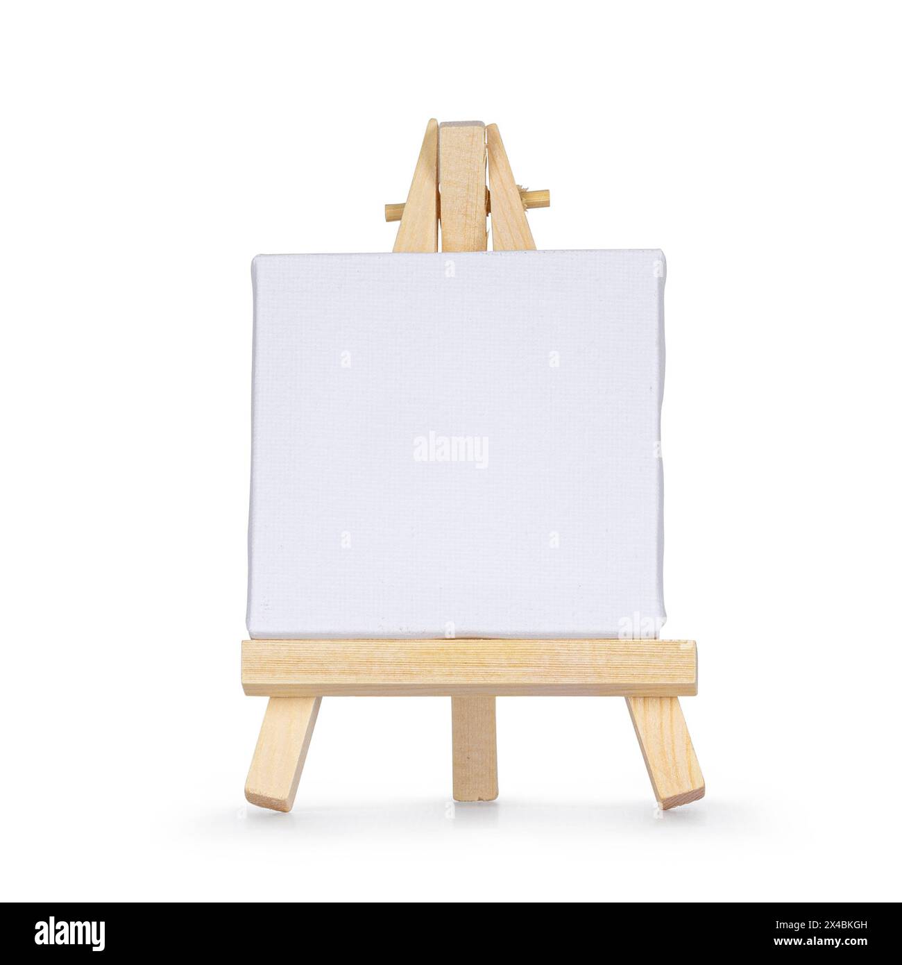 Tiny wooden painters easel with emtpy white canvas, standing facing front. Isolated on a white ...
