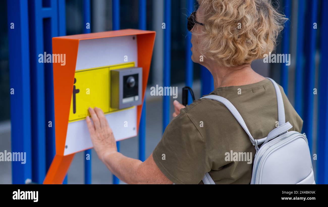 An elderly blind woman reading a text in braille. Button for calling ...