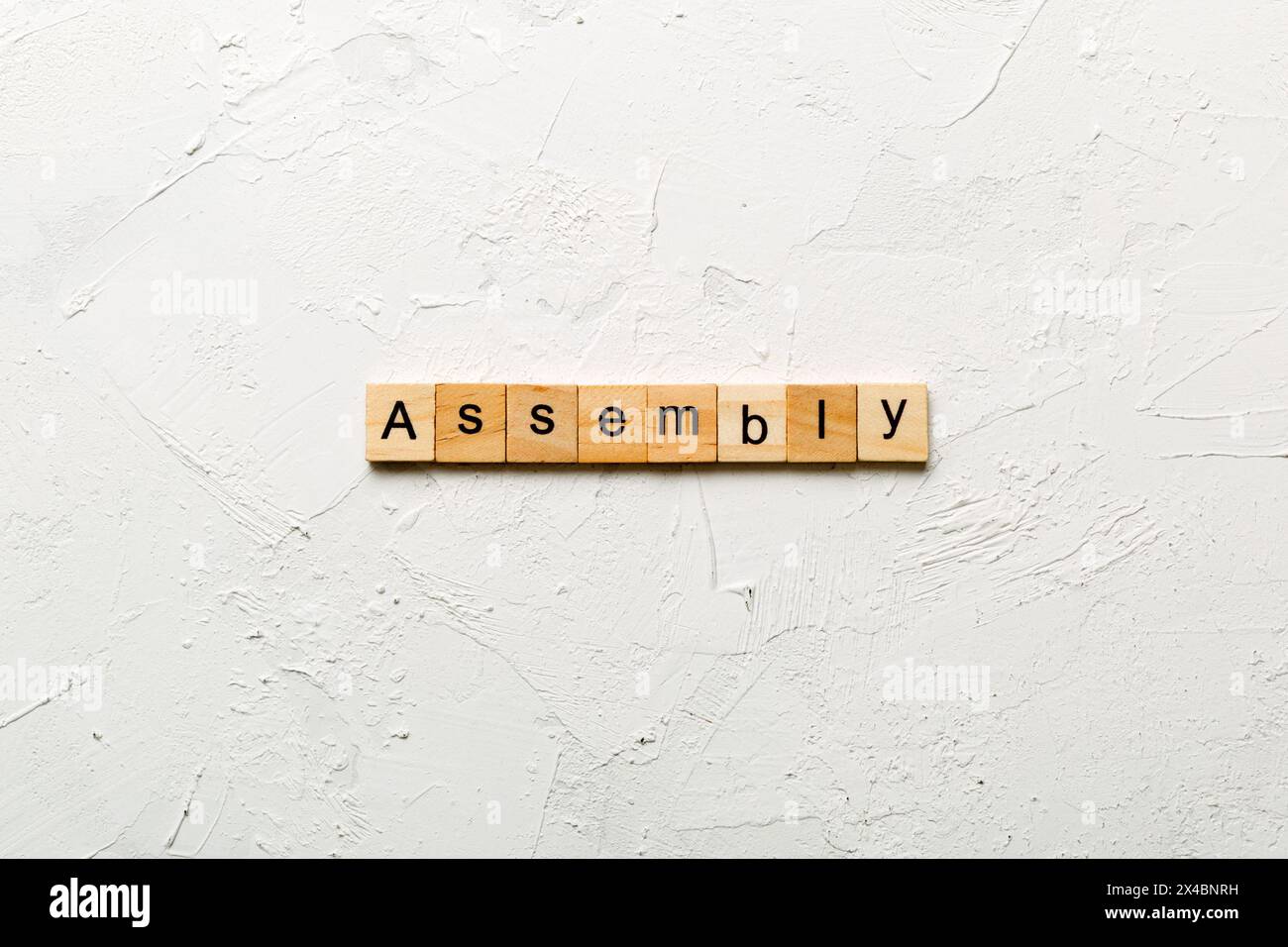 ASSEMBLY word written on wood block. ASSEMBLY text on cement table for ...