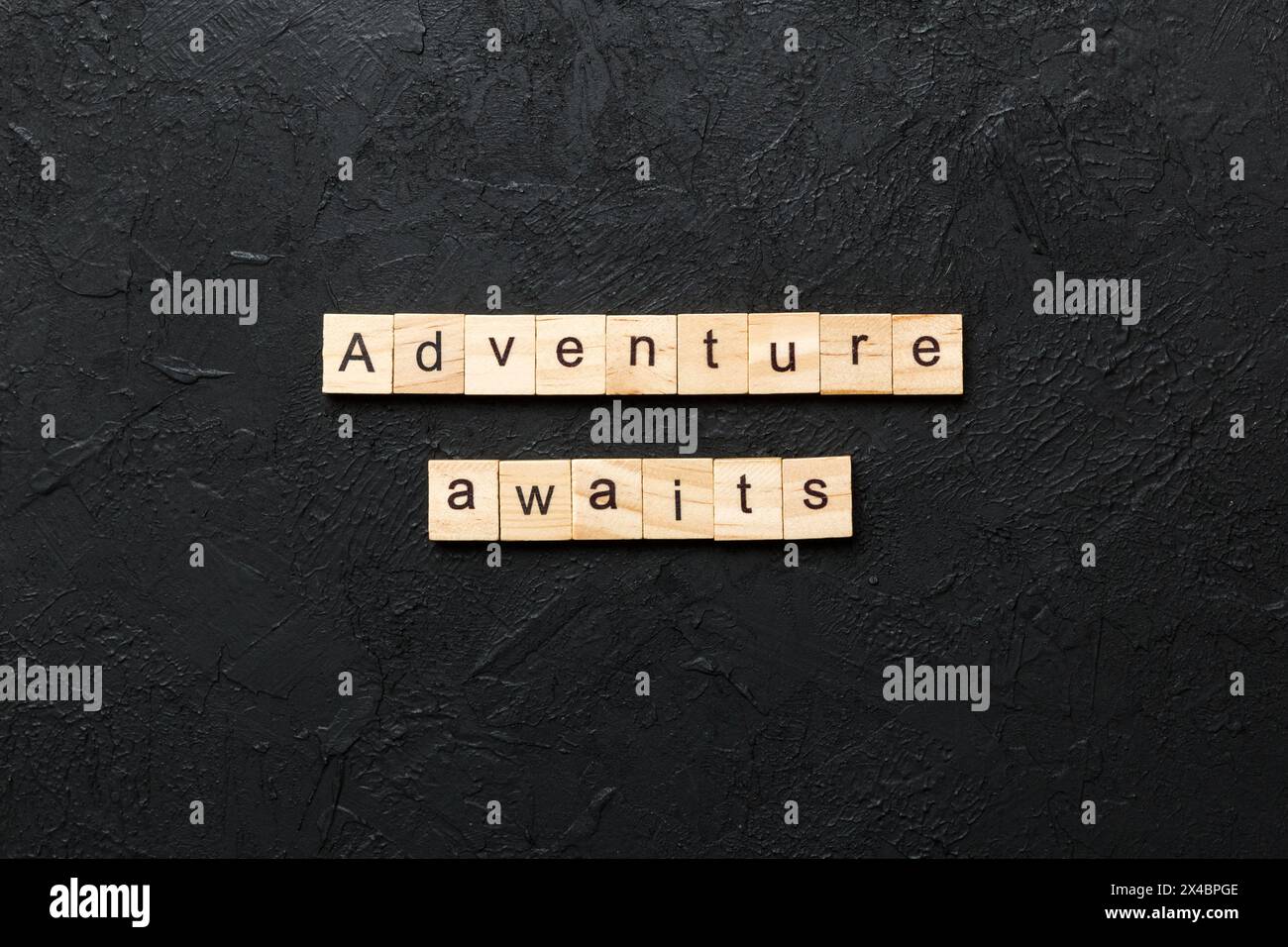 Adventure awaits word written on wood block. Adventure awaits text on ...