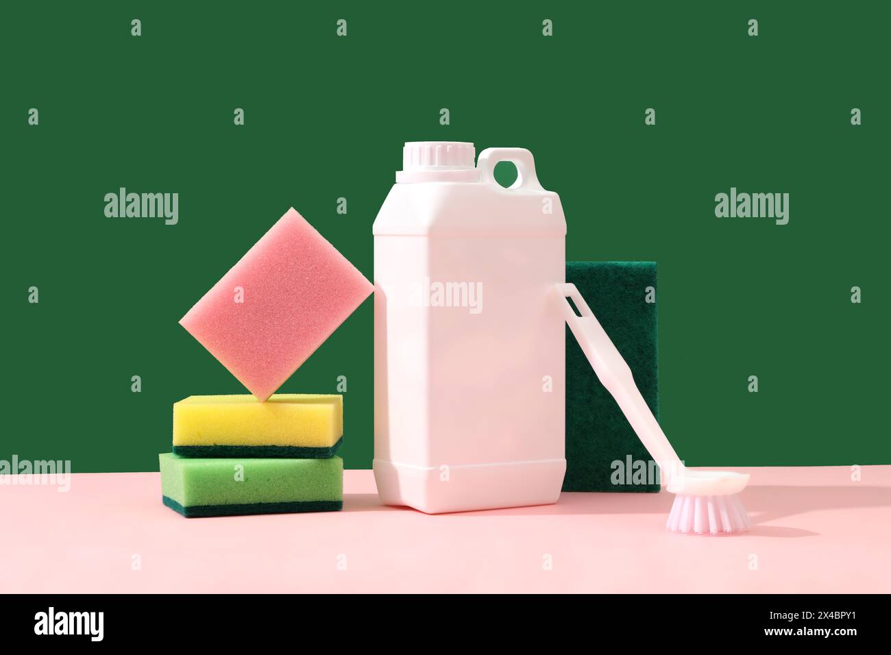 Colorful cleaning products on a green background and pink plain with ...