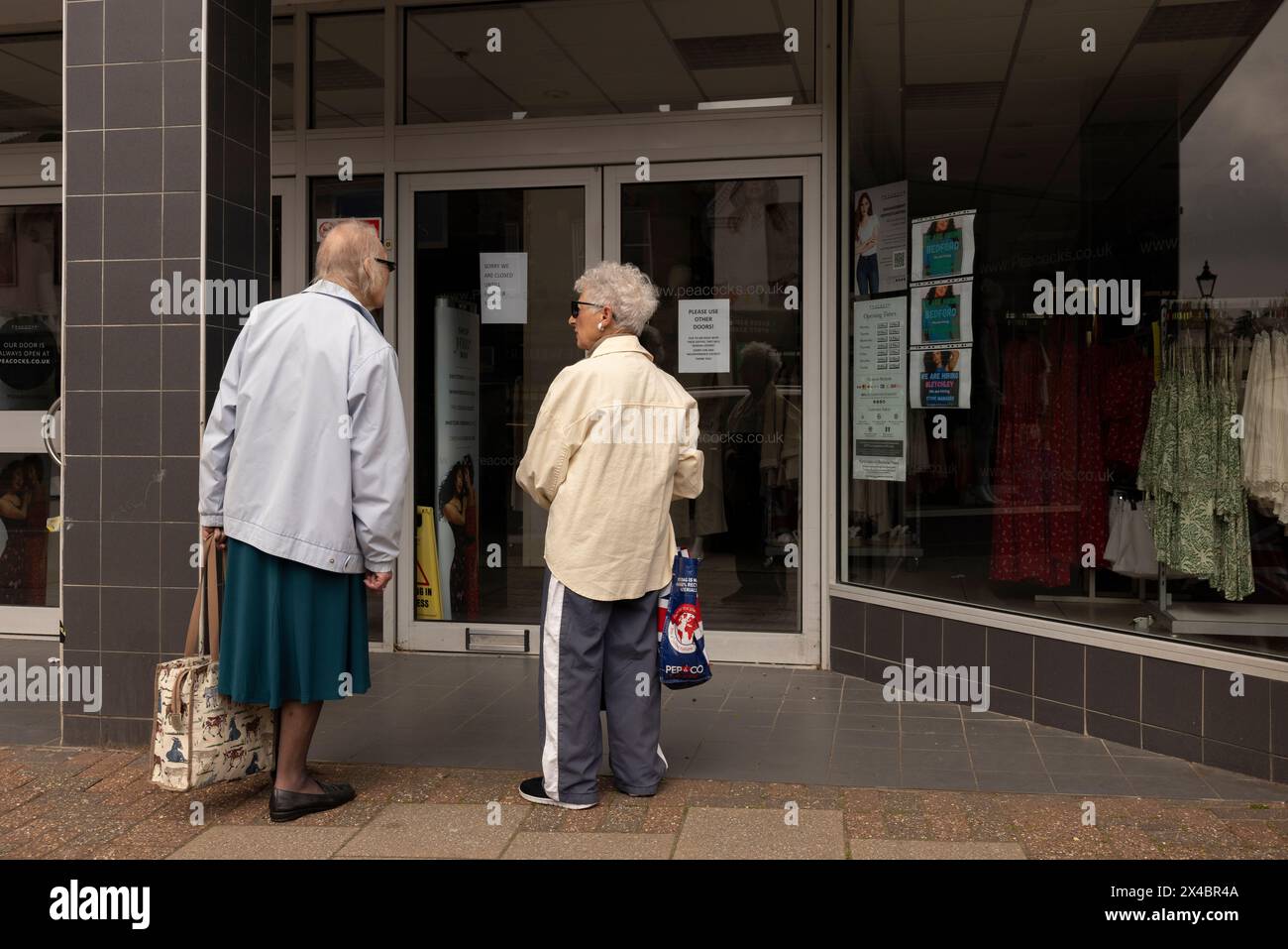 Two elderly ladies at the window display of PEACOCKS clothing ...