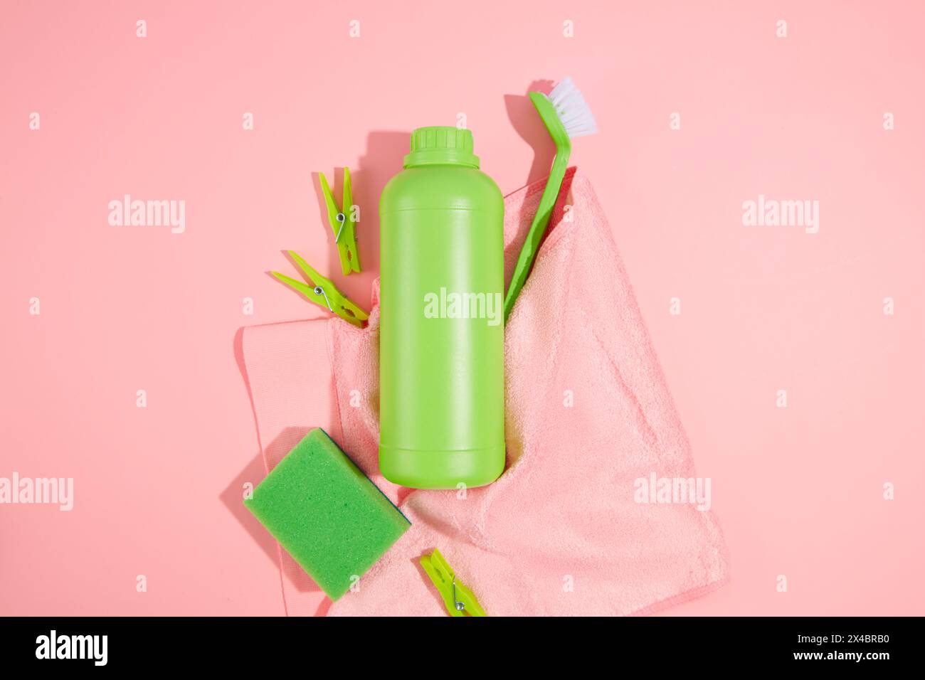 Against a pink background and pink wipe, green bottle of detergent with ...