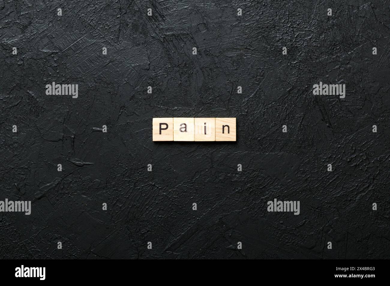 PAIN word written on wood block. PAIN text on cement table for your ...