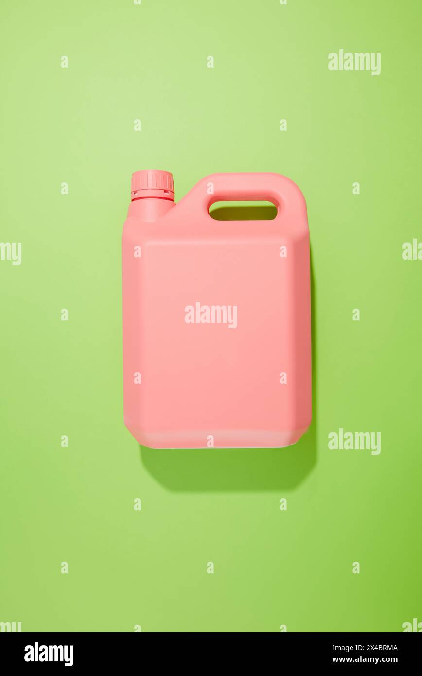 On a green background, a pink plastic canister of detergent without a ...