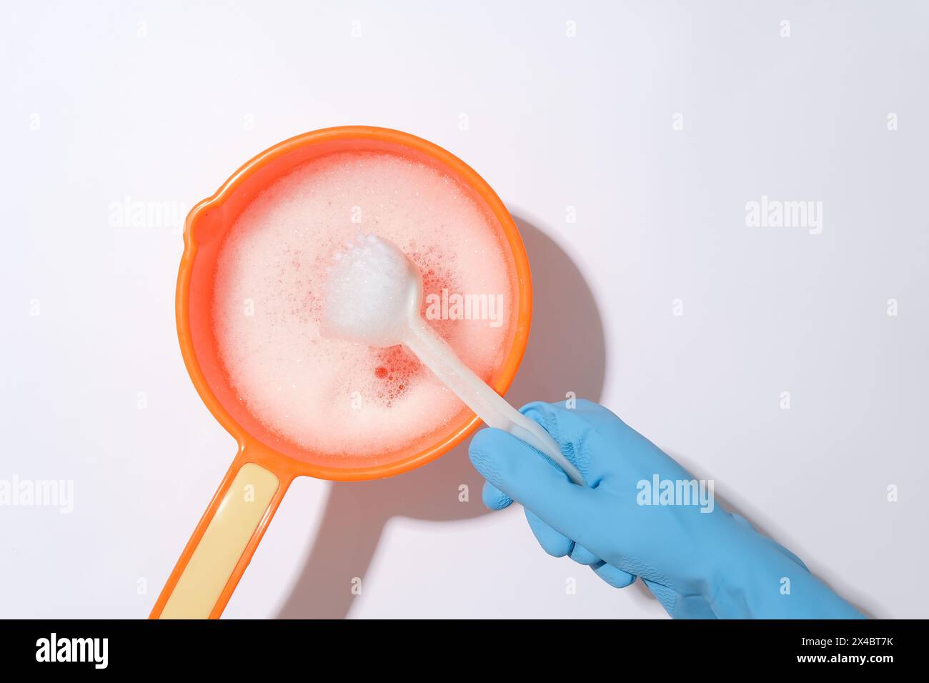 Hand wearing rubber gloves holding a toilet brush dipped in a plastic ...