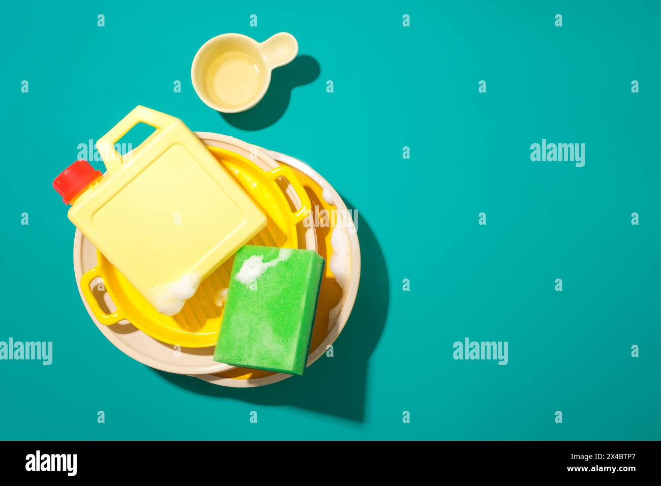 A bottle of detergent and a sponge are placed on top of a pile of dirty ...