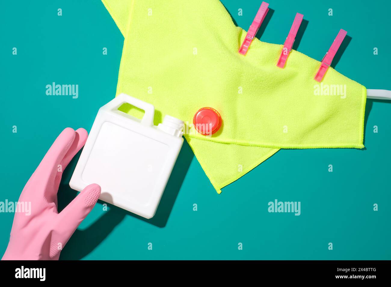 Top view of a white detergent bottle, one hand wearing a pink rubber ...