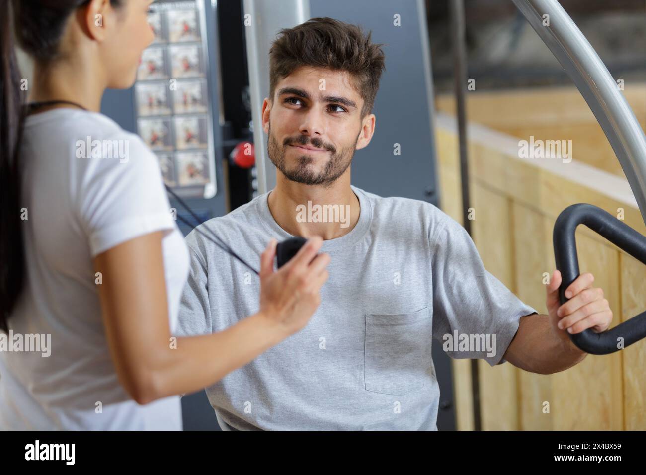 personal trainer showing time to man using gym machine Stock Photo - Alamy