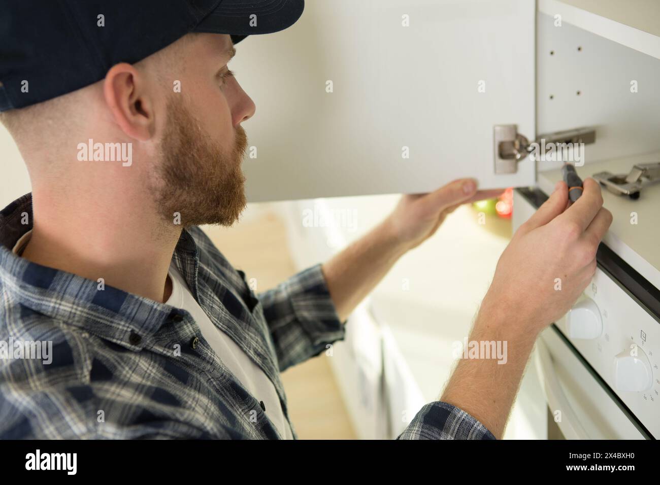 man posing while fixing cupboard hinges Stock Photo - Alamy