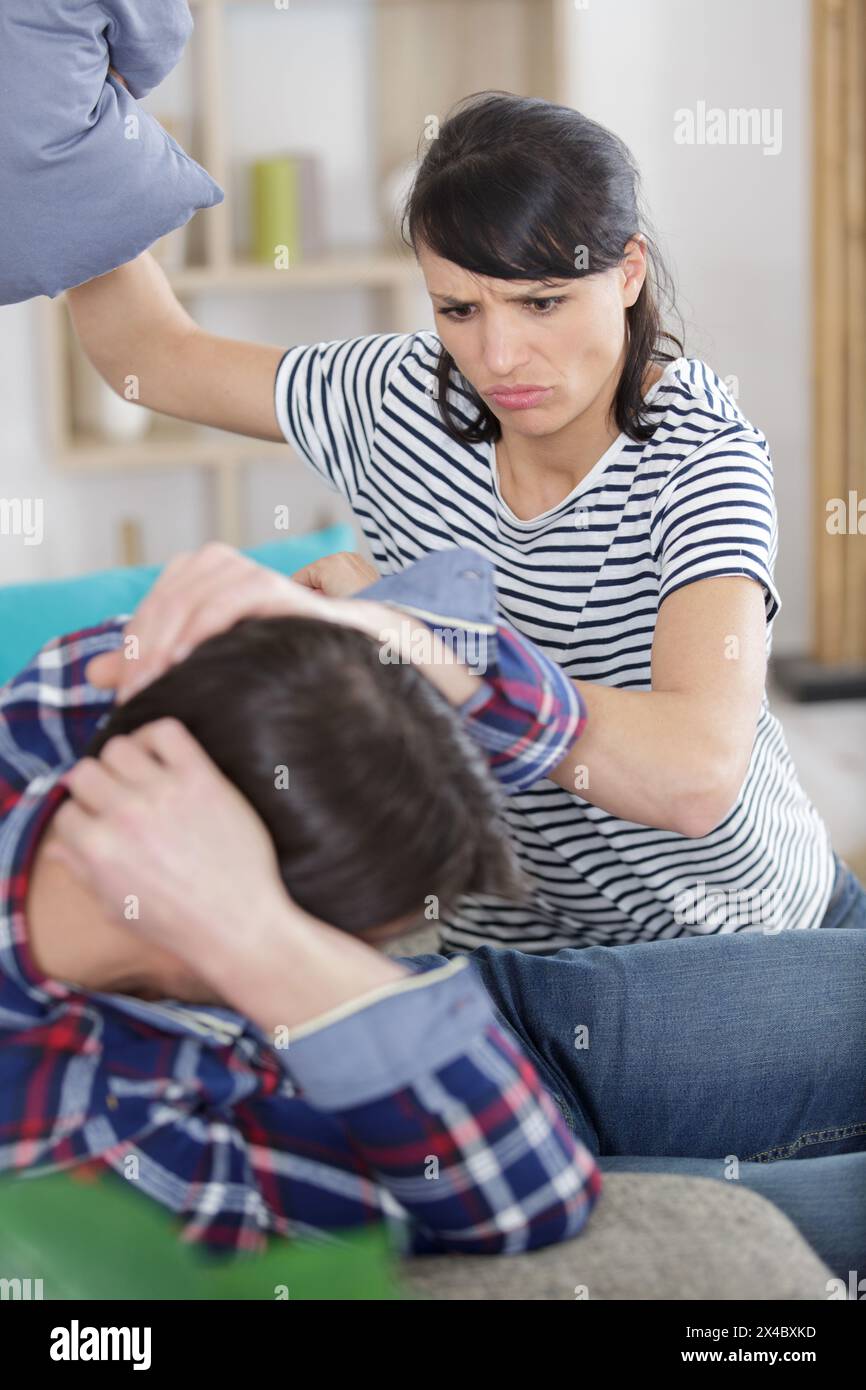 woman angrily hitting boyfriend with a cushion Stock Photo - Alamy