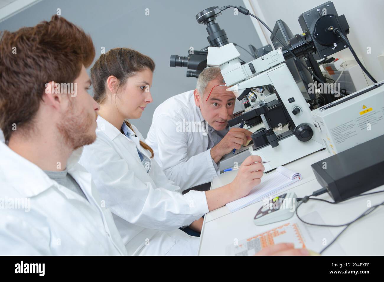 teacher with students using microscope in science class Stock Photo - Alamy