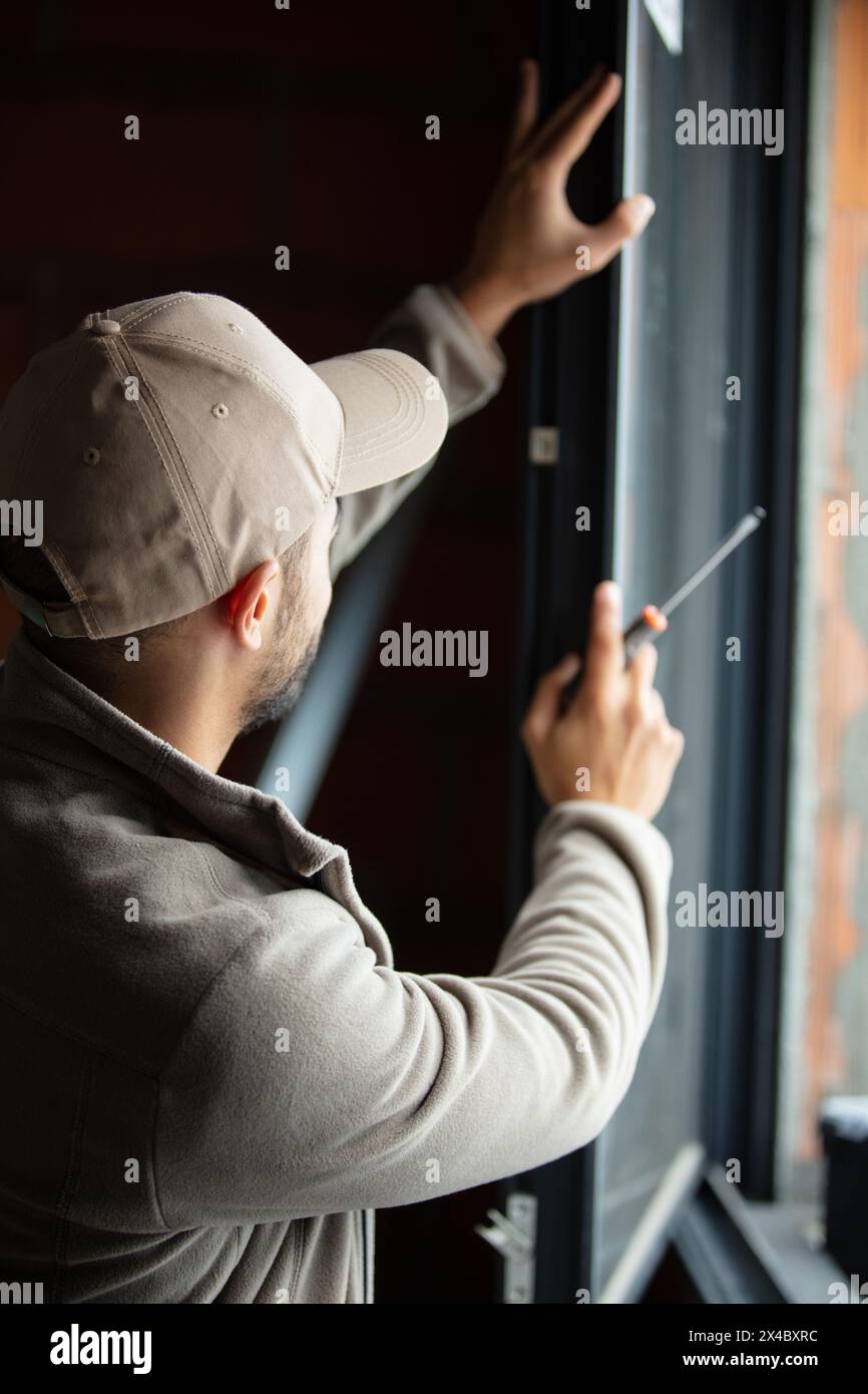 service man installing window with screwdriver Stock Photo - Alamy