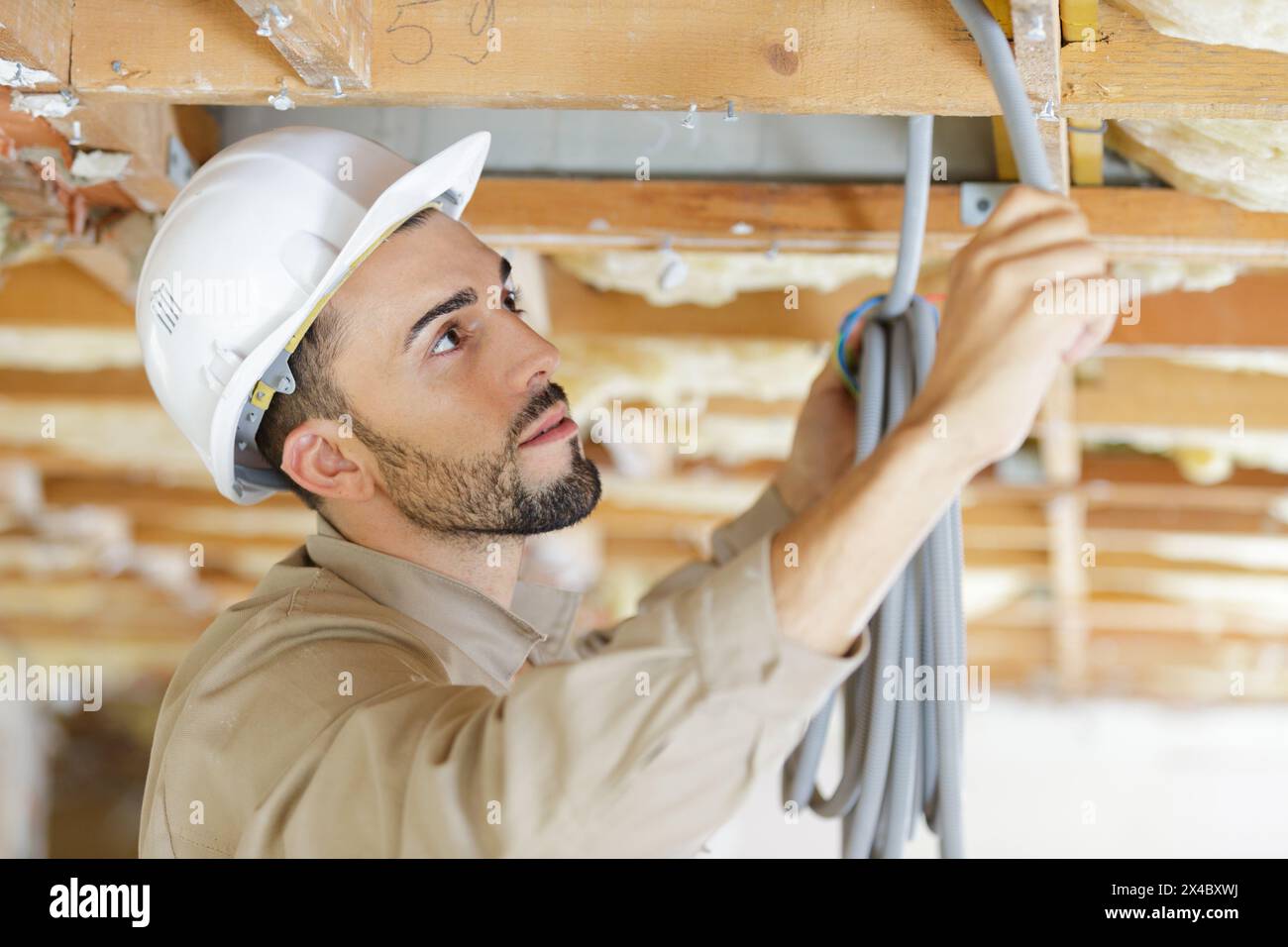 contractor passing cables through framework of ceiling Stock Photo - Alamy