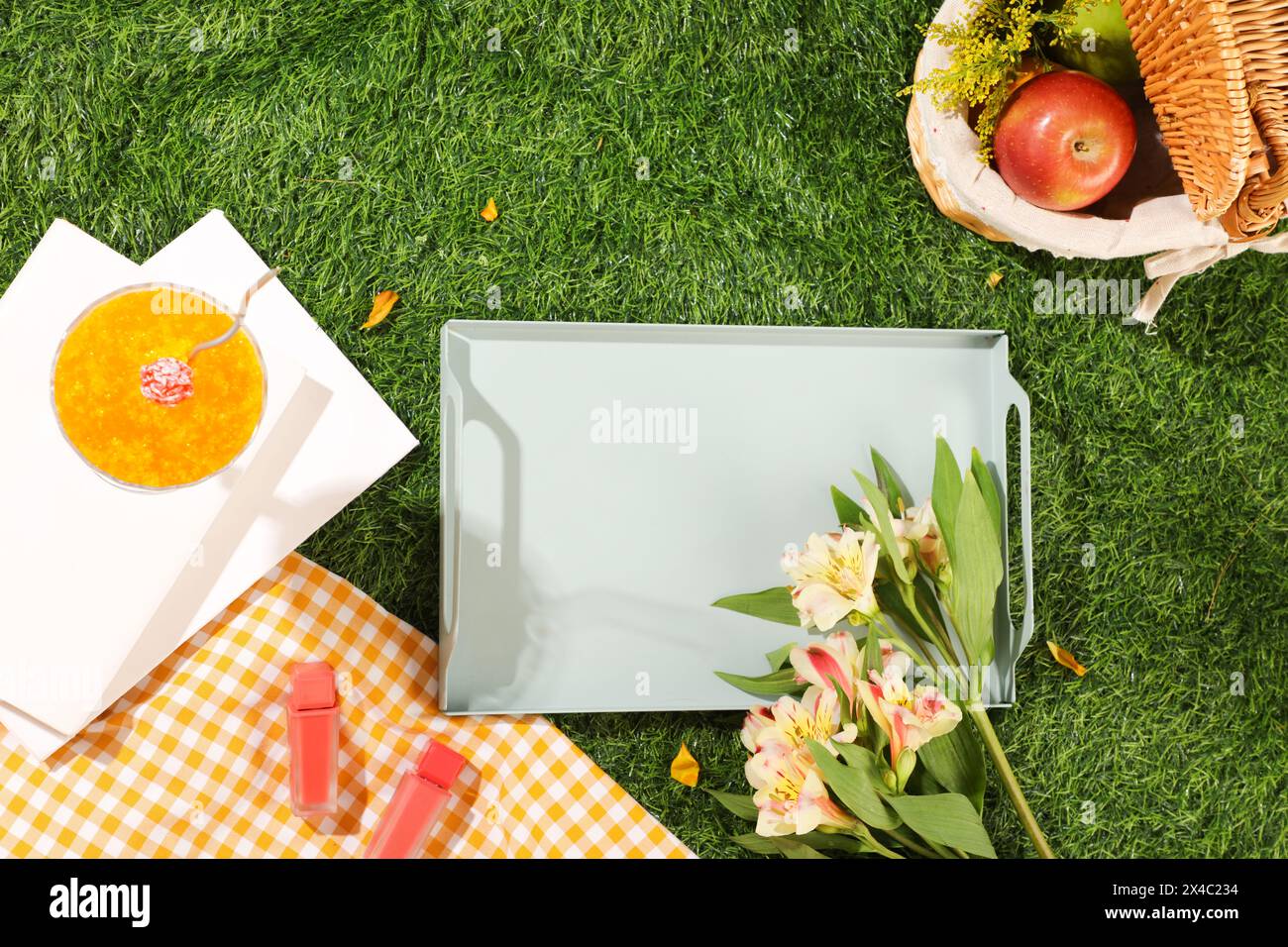 On a green grass background, basket of fruits, smoothies cup, lipsticks ...